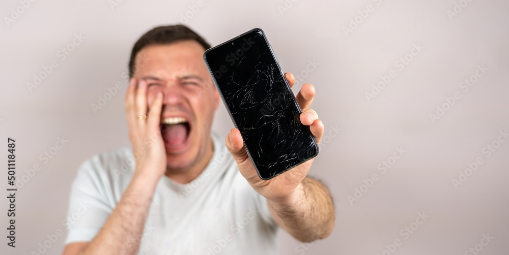 Frustrated man screaming from despair shows smartphone with cracked ...