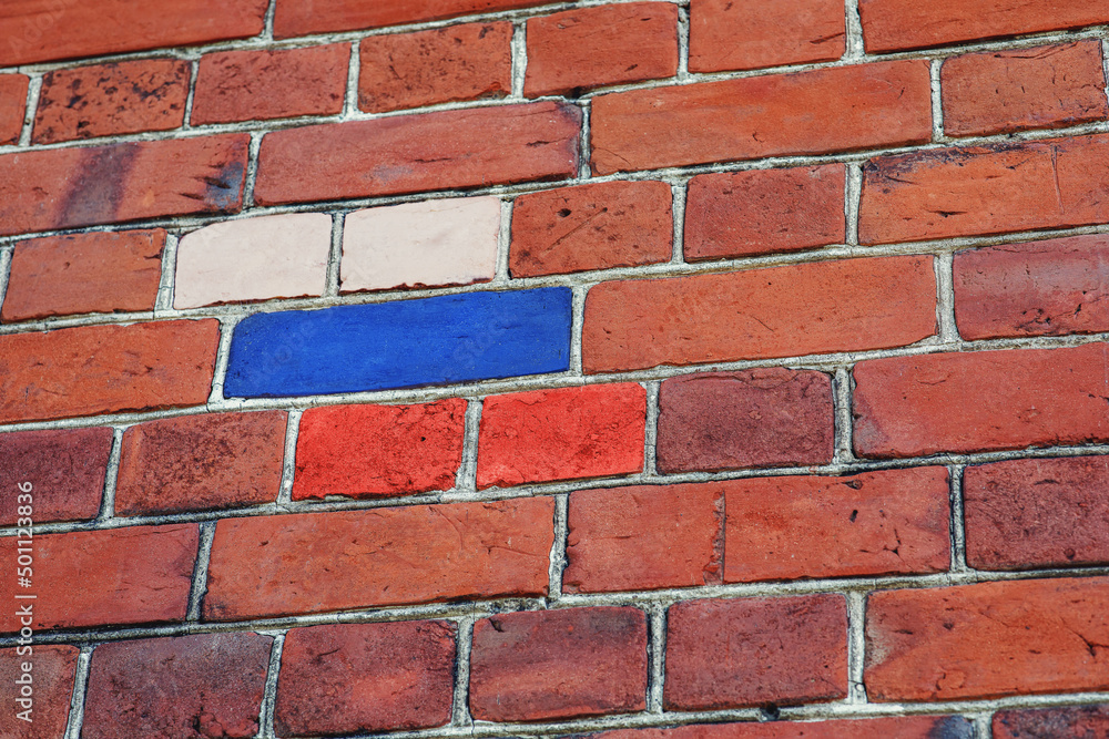The brick wall is painted in the colors of the Russian flag. Part of ...