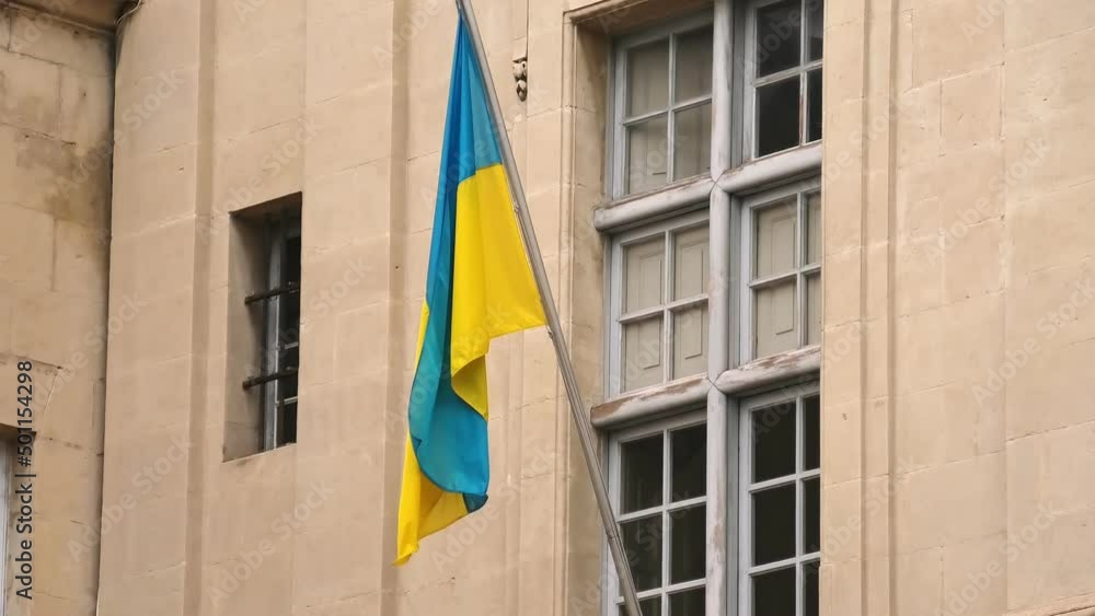 The Ukraine flag at the window waving in the wind. In support of the ...