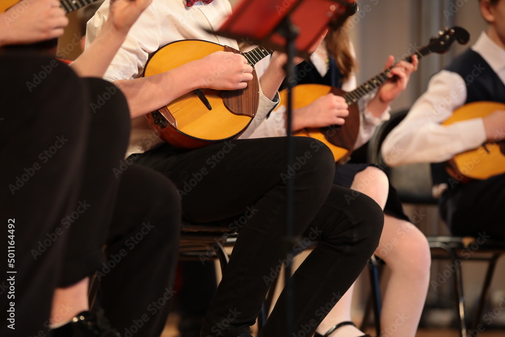 A balalaika in the hands of a young musician playing in a group of ...
