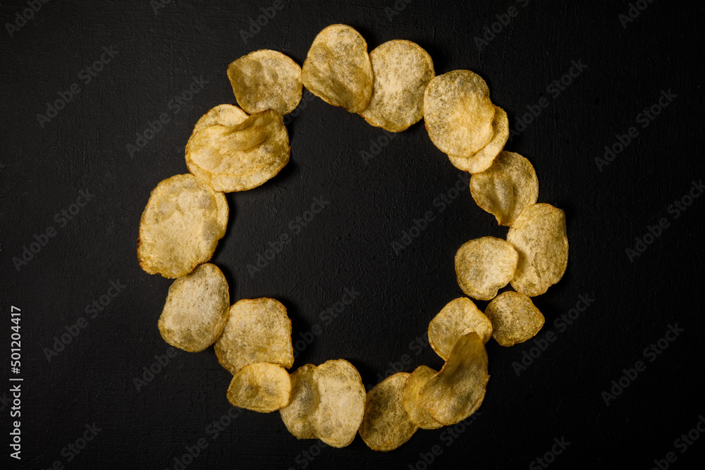 Crispy potato chips on a black background. Chips in the idea of a ...