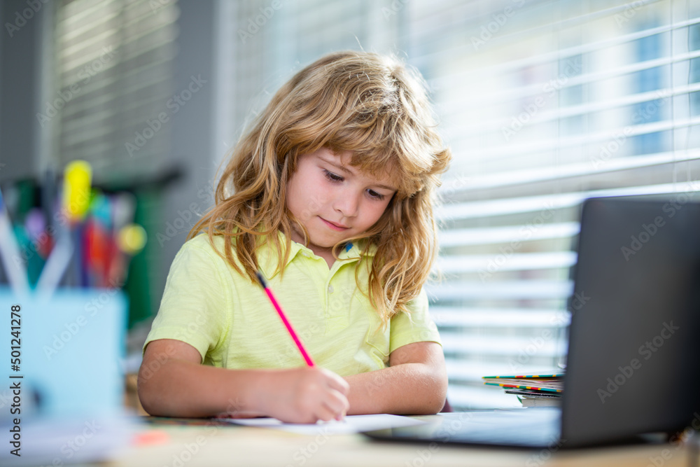 Child writing homework in school class. School boy making notes in ...