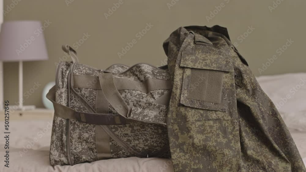 No people slowmo of military uniform and army beg on bed in olive green ...