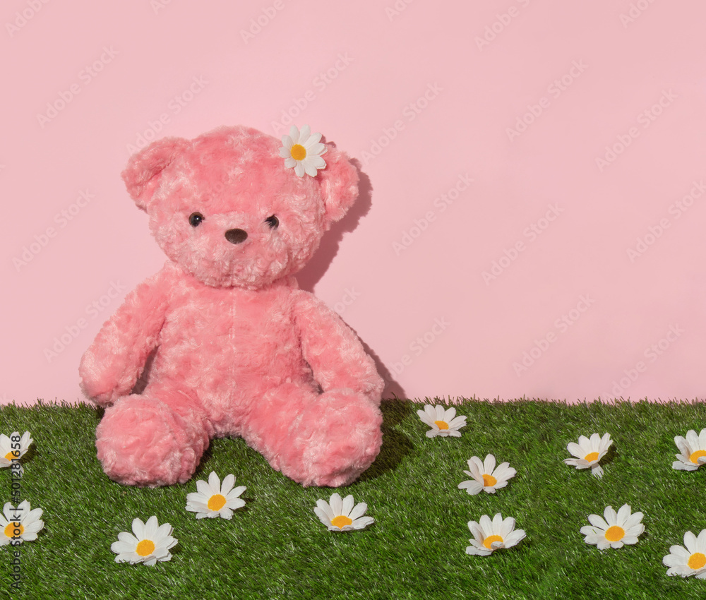 Spring creative layout with pink teddy bear sitting on grass with white ...