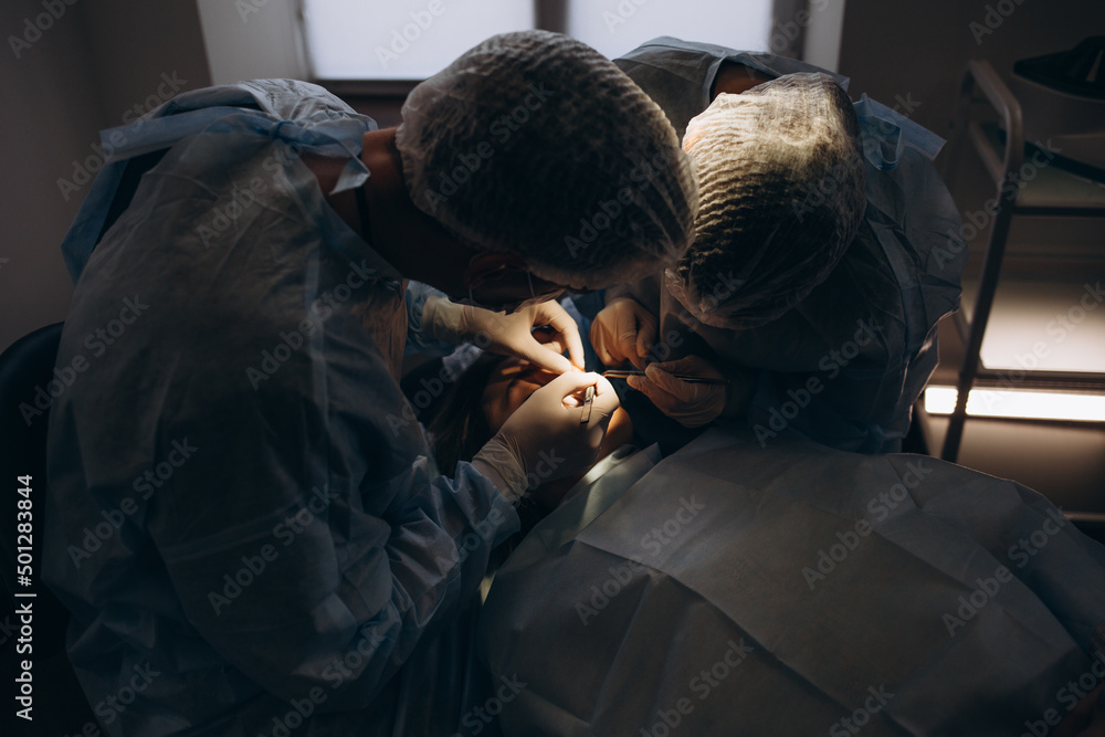 Surgeon and his assistant performing cosmetic surgery on nose in ...