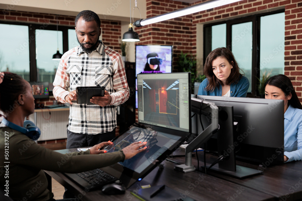 Game industry developer with multiple displays on desk working on level ...
