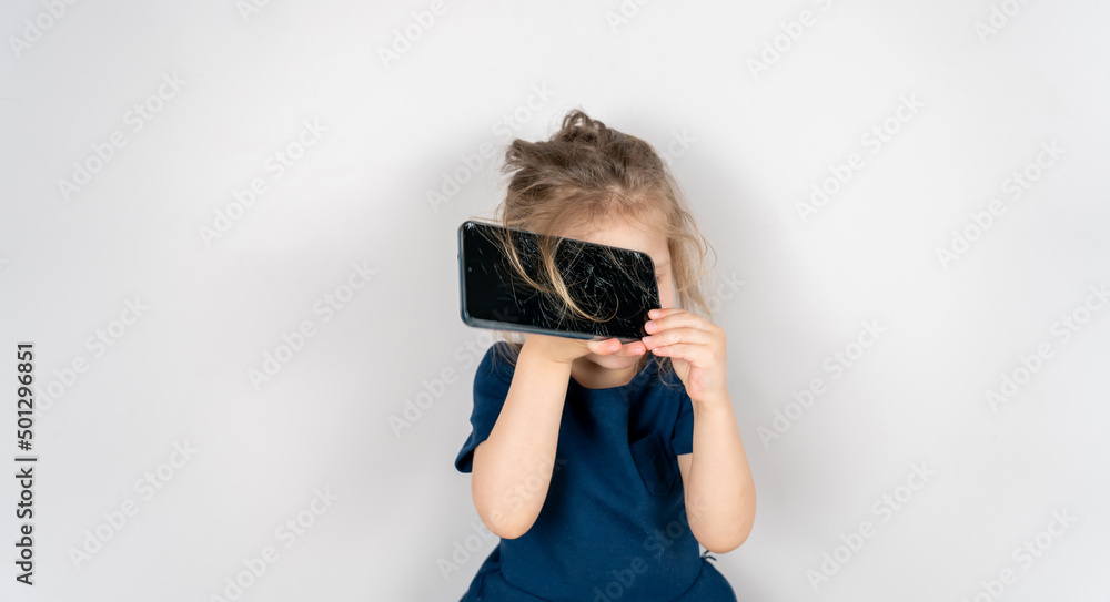 Portrait of terrified child with damaged phone. Upset little girl ...