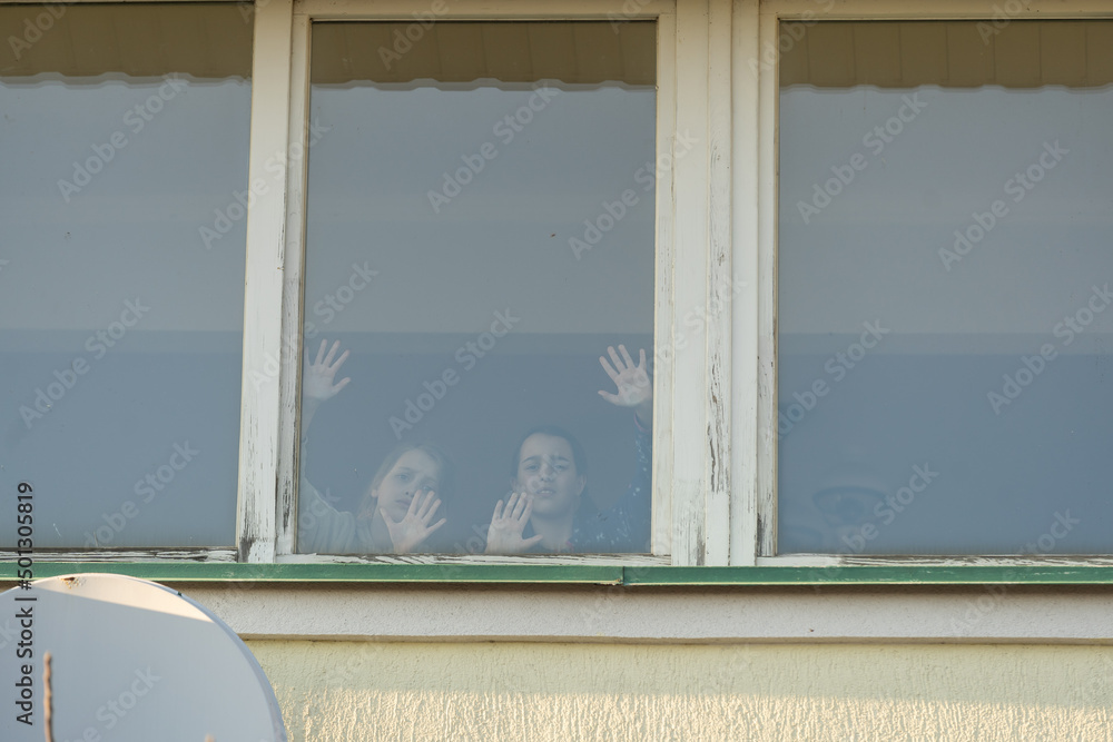 Little children with a sad look. Sad kids by the window. A child cries ...