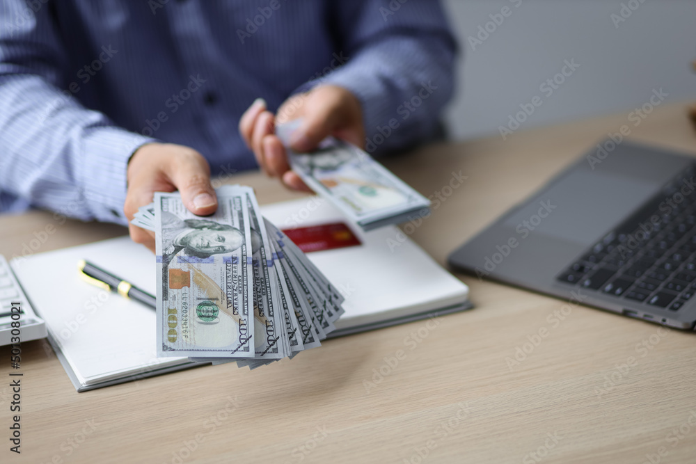Wealthy businessman counting money and holding cash on his desk is ...