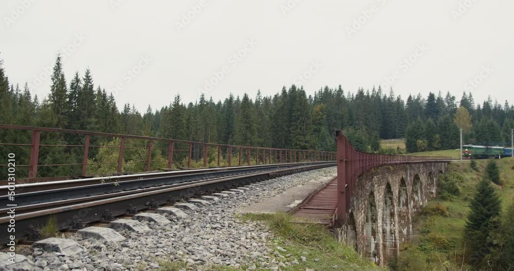 Train goes over the bridge with an old stone viaduct. Train crossing a ...