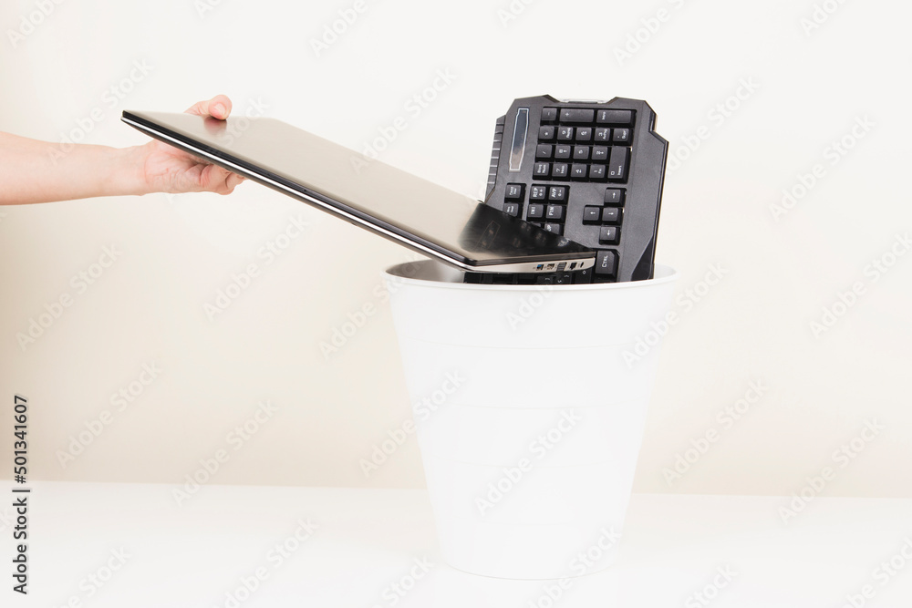 Hand puts used laptop computer into recycling bin full of old ...
