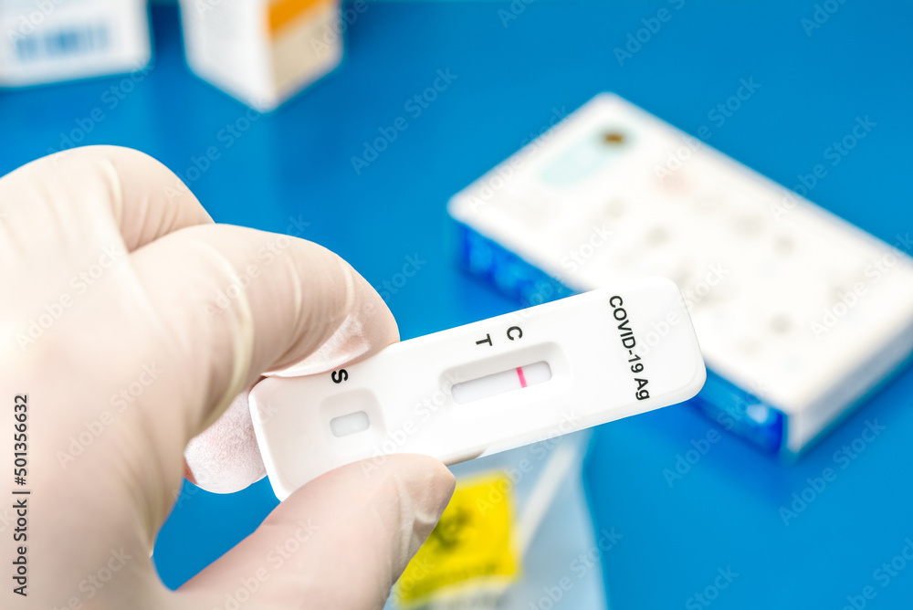 Gloved hand holding a Covid-19 rapid antigen test strip showing a ...