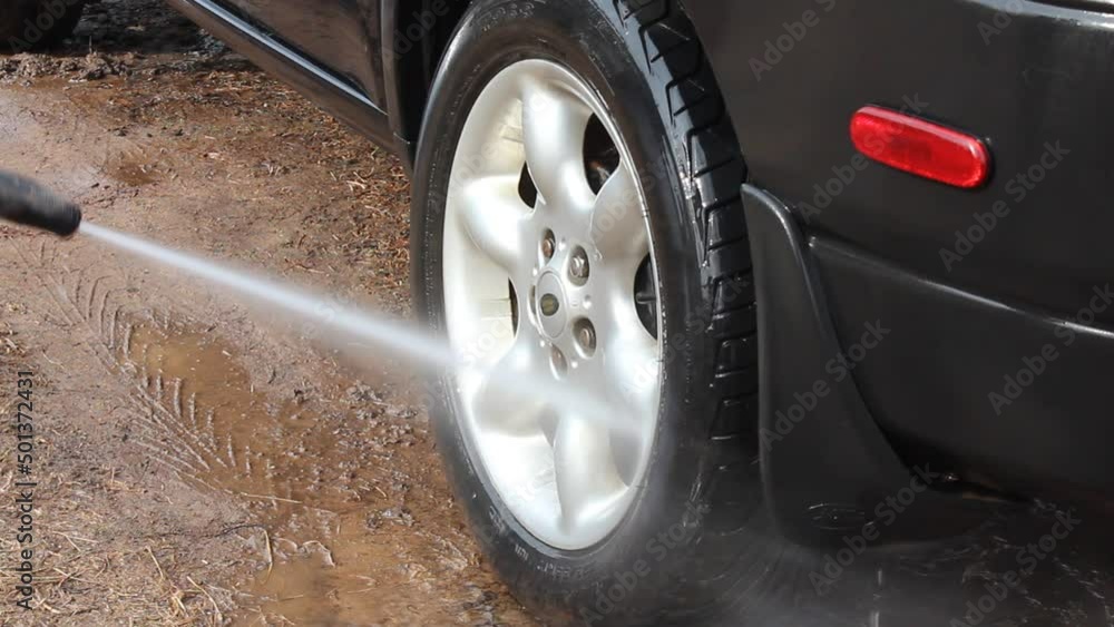 Manual washing of car with pressurized water in car wash outside. Close ...