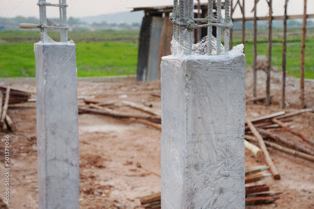 Concrete columns at the construction site are covered with plastic ...