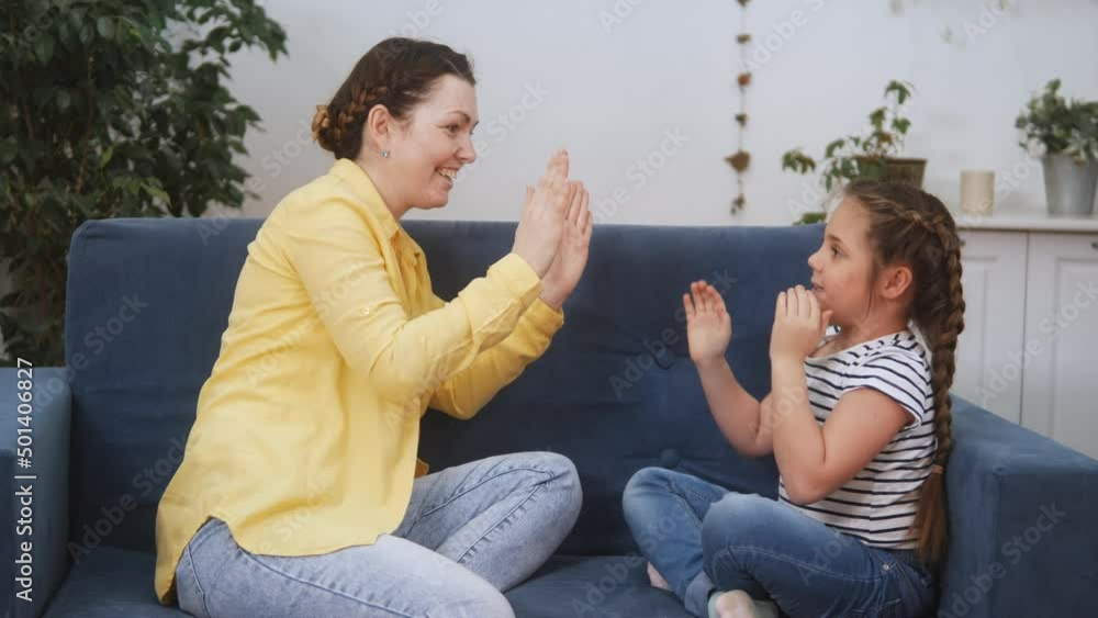 mom plays with her daughter at home a clap your hands happy family kid ...