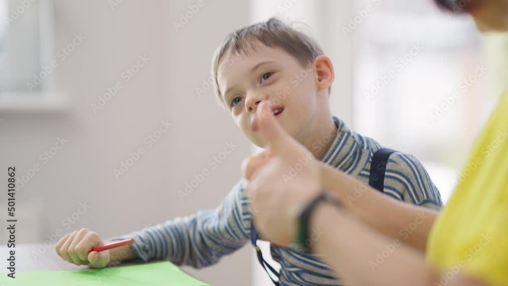 Portrait of excited autistic boy smiling as blurred unrecognizable ...