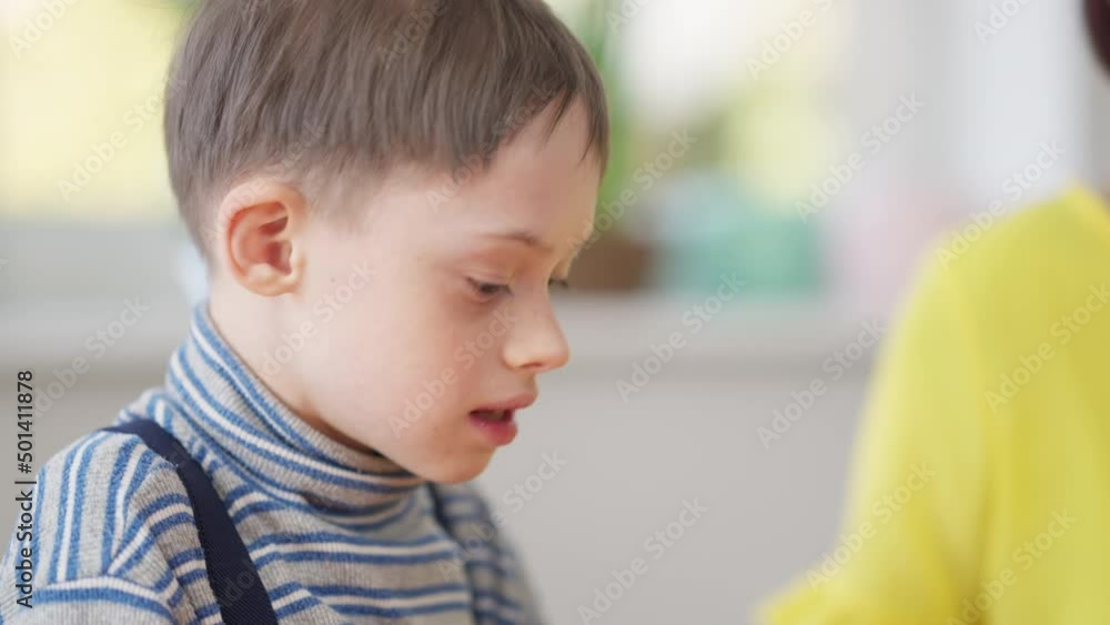 Side view smiling autistic curios boy licking palm choosing colors for ...