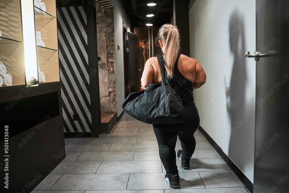 Dwarf sports woman going to the training through the hall at the modern ...