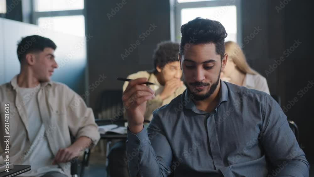 Young excited arab guy student sitting in classroom cannot concentrate ...