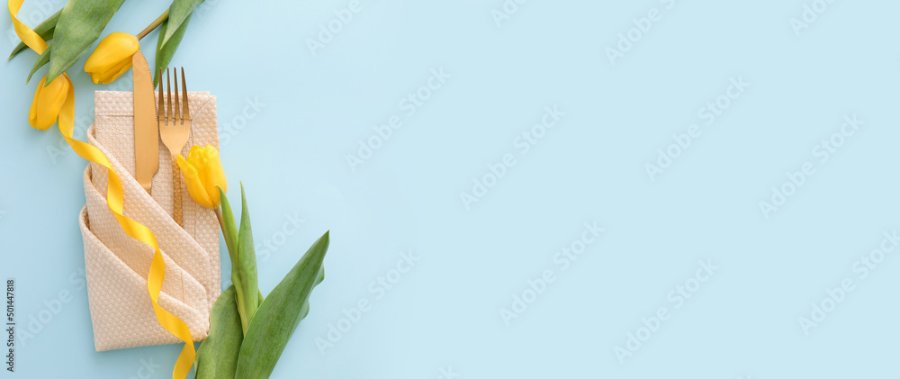 Napkin, cutlery and tulip flowers on light blue background with space ...