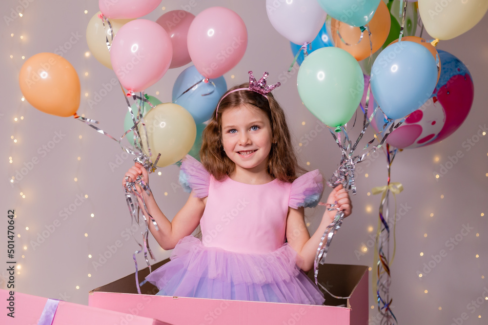 beautiful little girl with balloons jumps out of a huge pink box. child ...