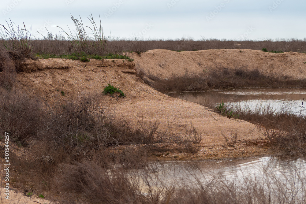 An abandoned shell quarry, flooded with water and dry grass. Protection ...