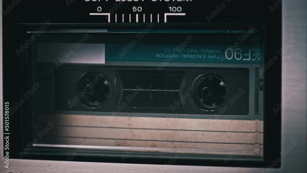 Audio cassette rotates in deck of old tape recorder. Audiocassette with ...