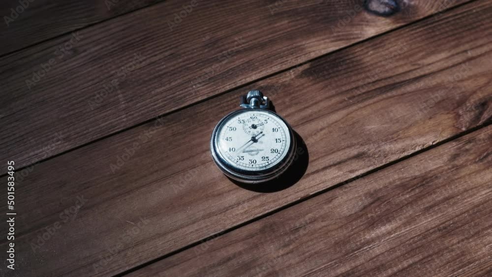 Antique stopwatch lies on wooden table and counts the seconds ...