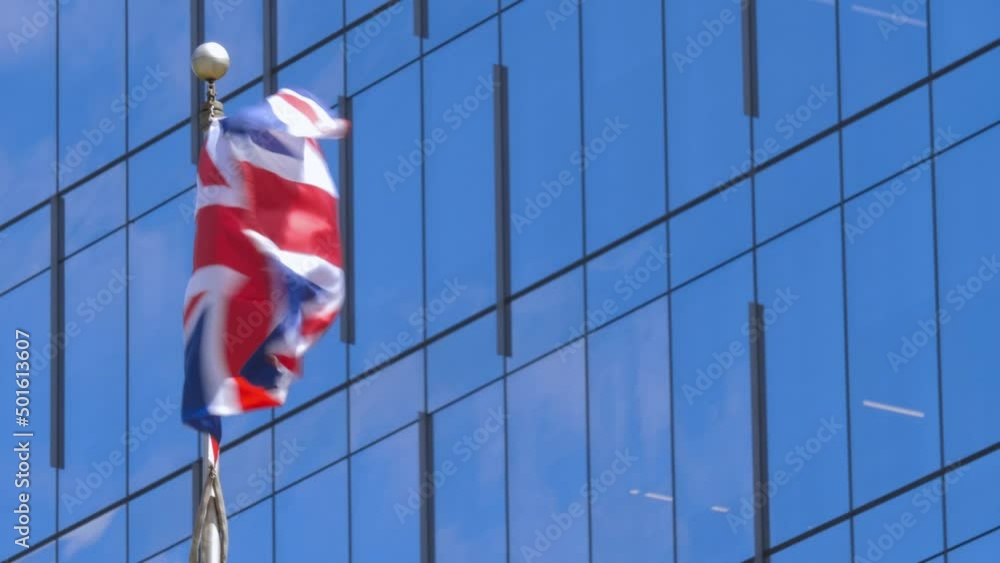 British national flag is waving in wind against modern building. Flag ...
