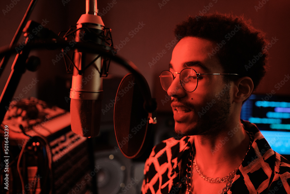 Portrait of young Black male singer working in recording studio ...