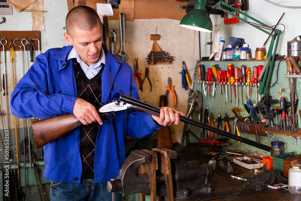 Gunsmith examines an automatic rifle before being repaired in a weapons ...