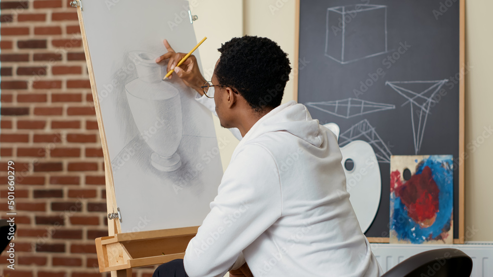 African american student using pencil to draw vase on canvas, learning ...
