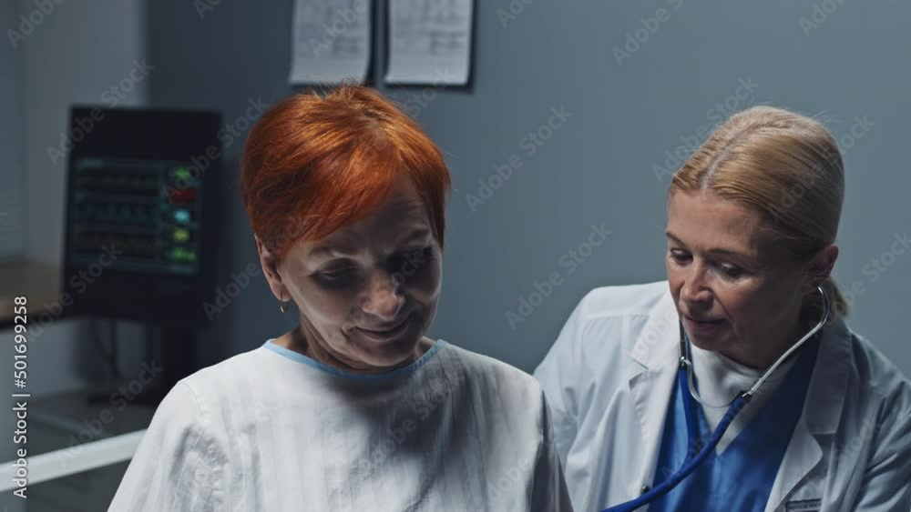 Chest up of blonde female doctor using stethoscope on mature Caucasian ...