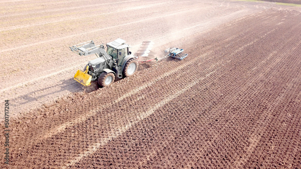Landwirt mit Traktor und Pflug bei der Arbeit auf dem Feld ...