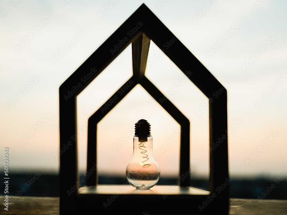Light bulb with wood house on the table, a symbol for construction ...