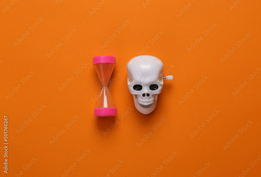 Clockwork skeleton skull toy with hourglass on orange background ...