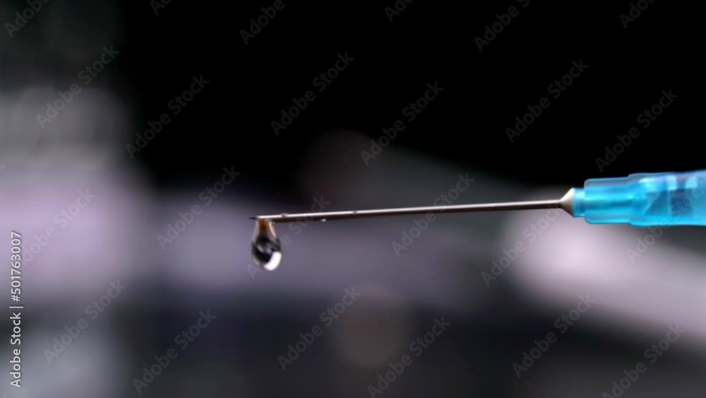 Learstvo is dripping from medical syringe, flowing down in large drops ...