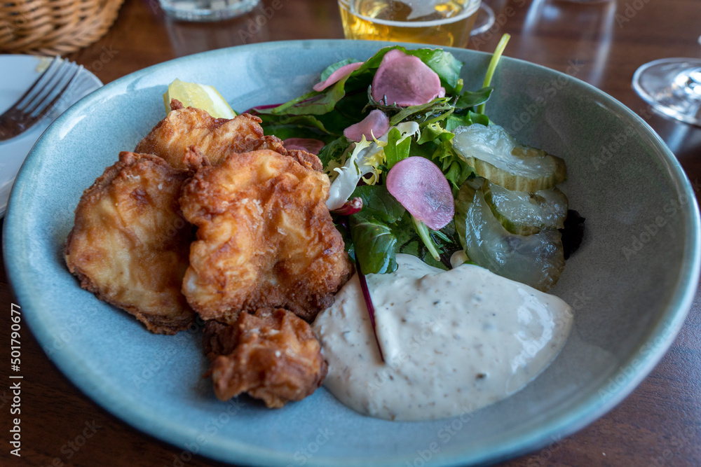 Fried tongue of cod fish with sauce and salad typical from Lofoten ...
