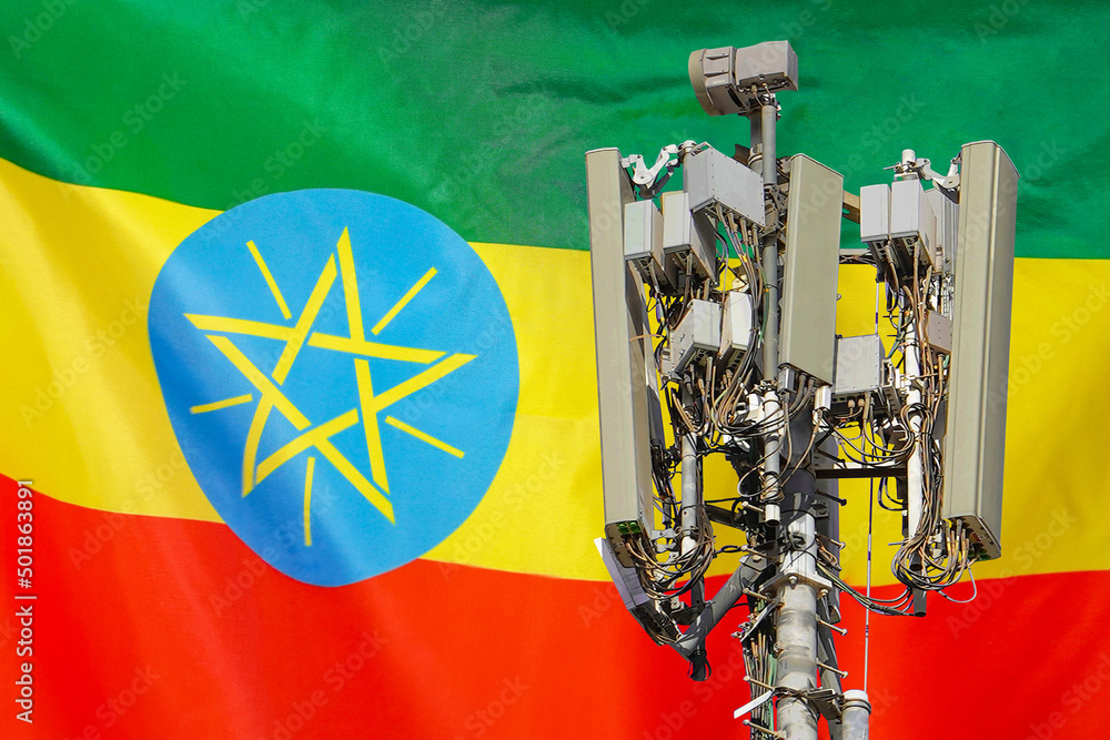 Telecommunications tower with a 5G cellular network antenna agains flag ...