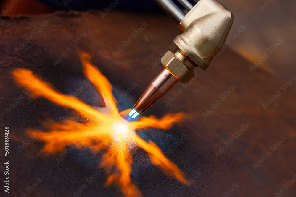 Gas cutting of metal. Gas cutter with copper nozzle with a stream of ...