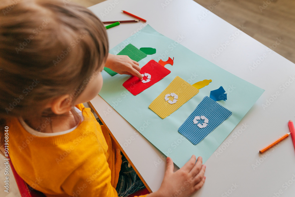Little girl playing with poster of garbage containers for sorting at ...