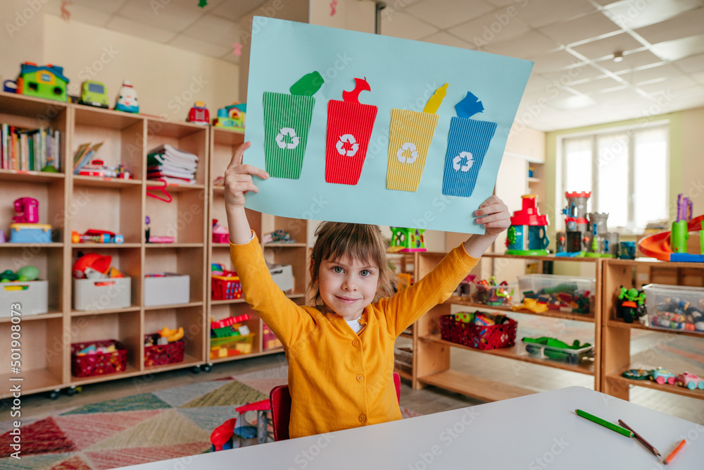 Little girl holding poster of garbage containers for sorting at ...