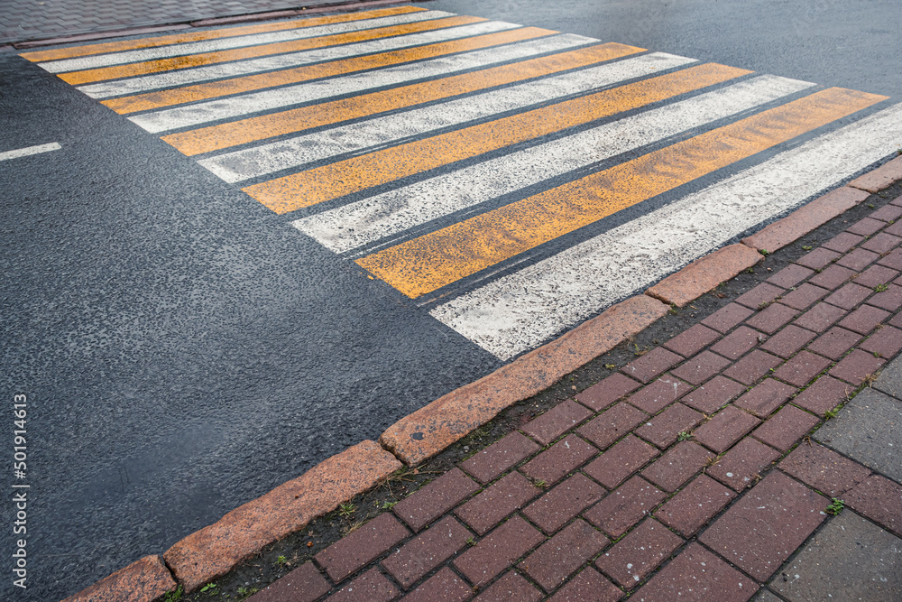 Sidewalk with lanes of pedestrian crossing on wet asphalt. Traffic ...