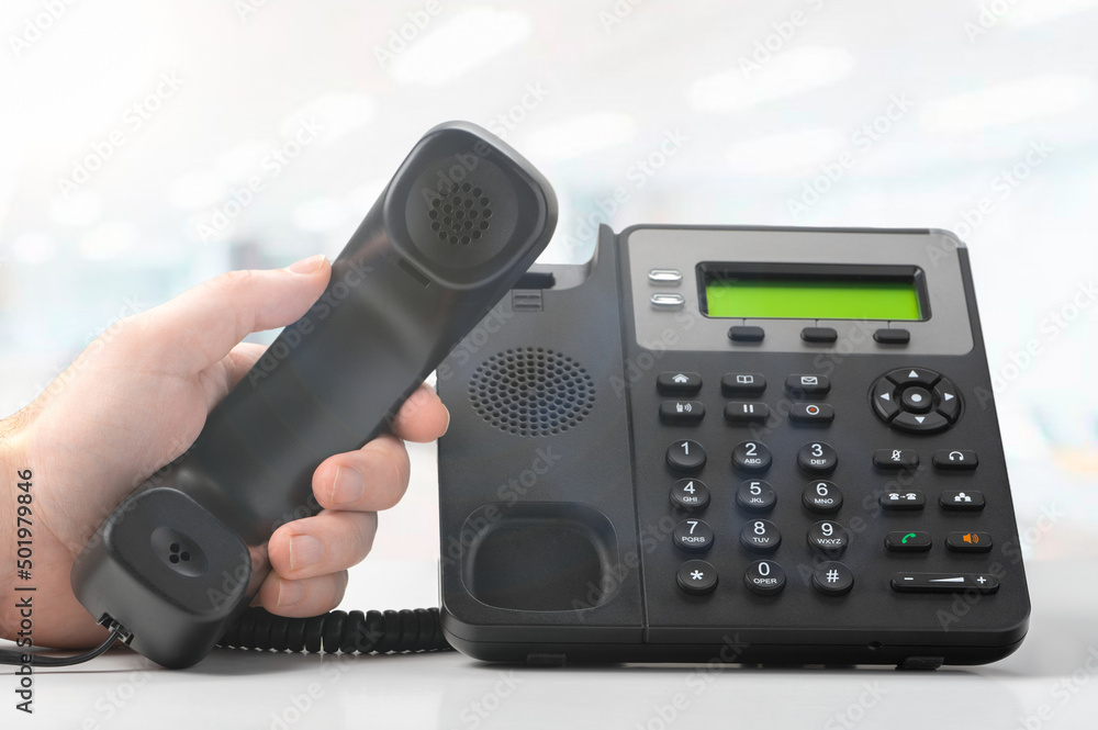 hand holding voip telephone receiver on blurred office background ...