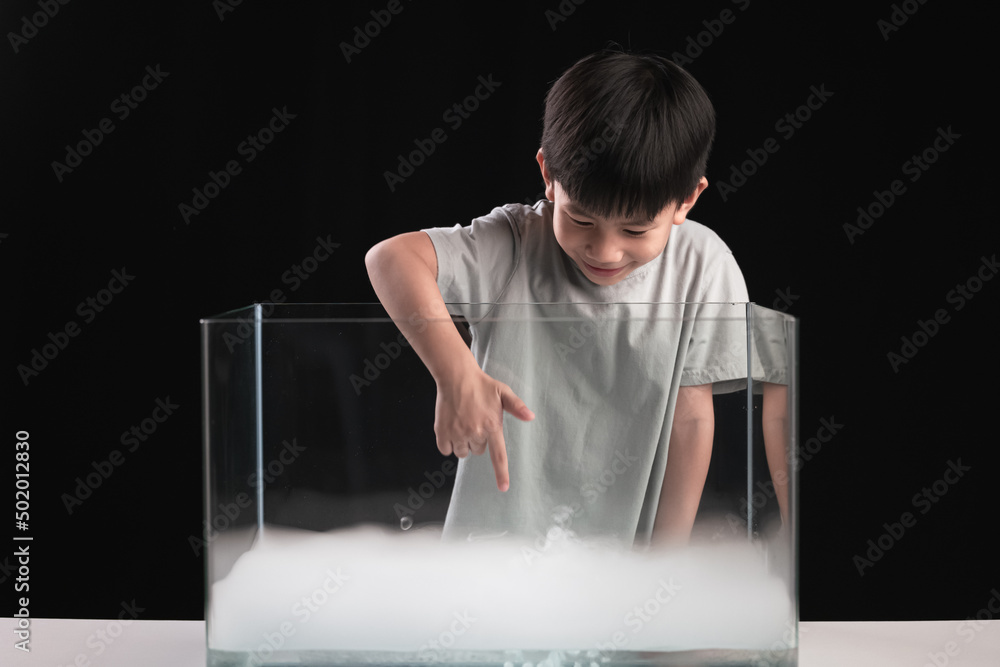 An Asian boy does an experiment with dry Ice or frozen carbon dioxide ...