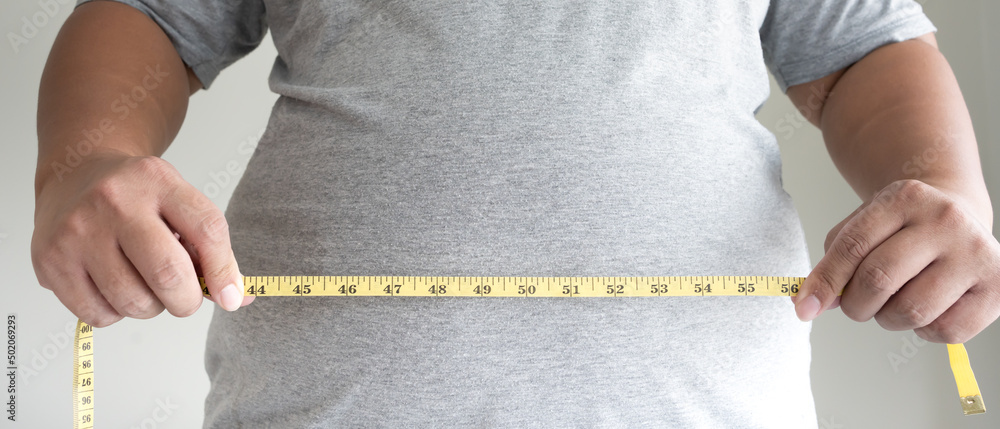 An obesity using measuring tape to show the real size. Chubby fat man ...