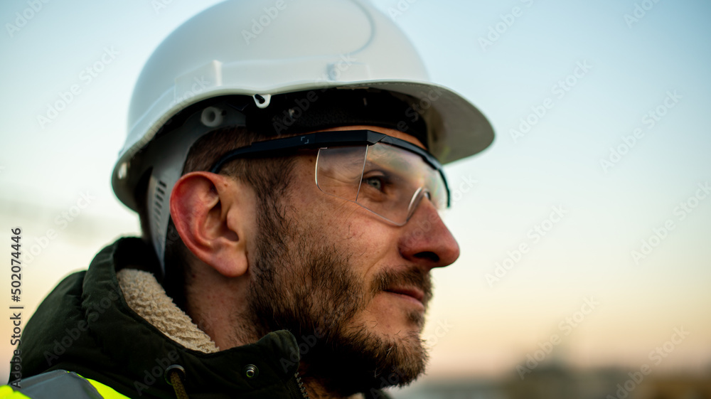 A construction worker in a hard hat helmet protect glasses looks ...