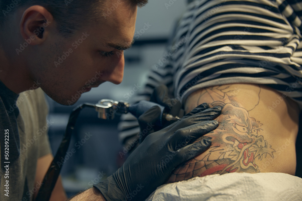 The master creates a picture on the body of a young beautiful girl ...