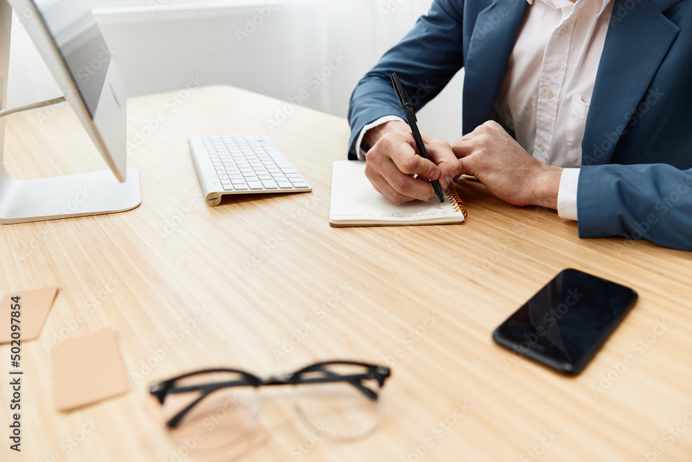 handsome businessman writes in documents at the desk in the office ...