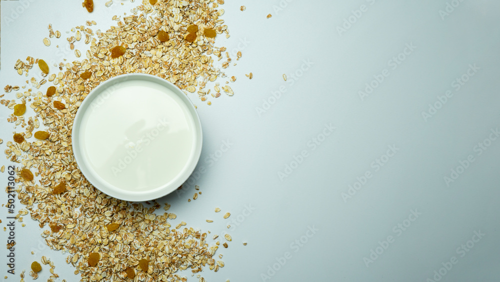 Scattered oat flakes on white background with milk in the bowl. Oat ...